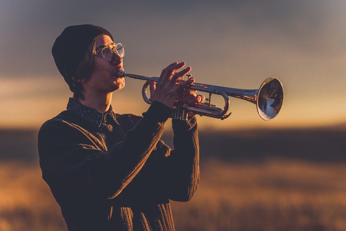 Free Photo: Young Man with Black Hat Playing a Trumpet at Sunset